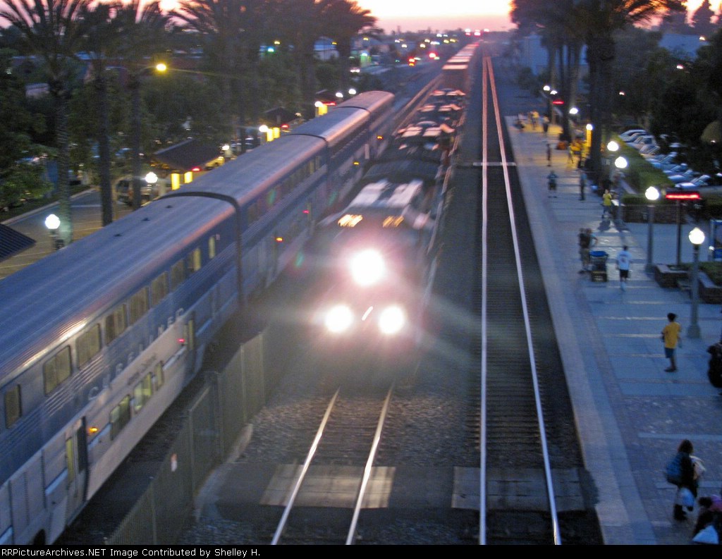 A BNSF train rumbling through the station as an amtrak sits on track 3